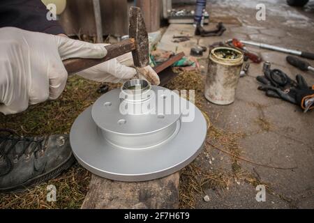 Hammering new bearing shell or race into car hub and brake disc using a ...