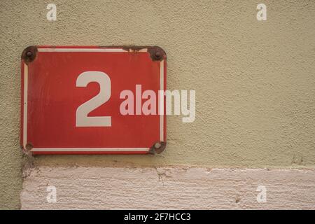 A house number, #3, mounted on a stone and brick wall along side a ...