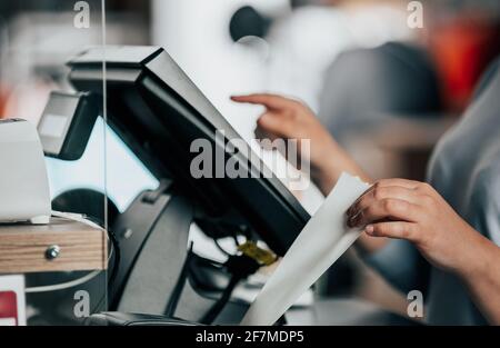 saleswoman or shopgirl printing a receipt or invoice for a customer ...
