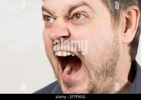 An angry aggressive man screams with mouth open. A human cry at a child ...
