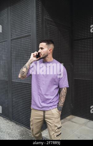 Spanish young man with tattoos talking on phone Stock Photo - Alamy