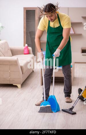 Young male contractor wearing prickly wreath on head doing housework ...