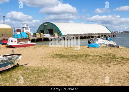 Warehouse dockyard building, small boats sandy beach foreground ...