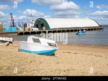 Warehouse dockyard building, small boats sandy beach foreground ...
