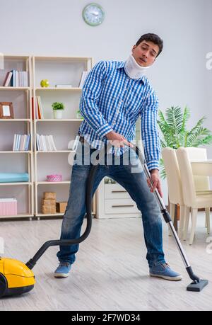 Injured man with neck injury vacuum cleaning house Stock Photo - Alamy
