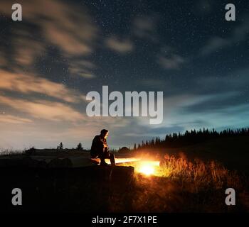 Side view of man lighting bonfire on field by river Stock Photo - Alamy