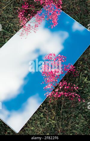 Amazing flat lay of a mirror on the grass, where you can see the clouds ...