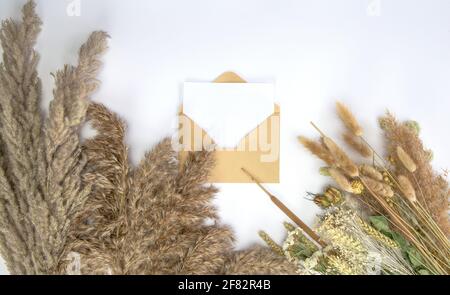 Minimalistic card mockup with reed flower, craft envelope, blossom ...