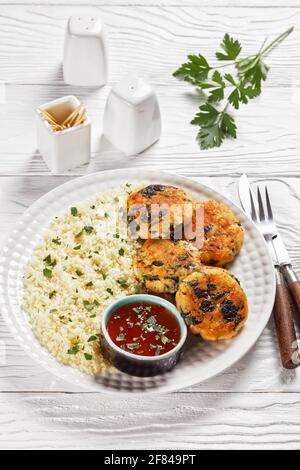 salmon and spinach fish cakes with couscous and sweet chili sauce on a ...