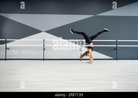 Fit female dancer doing side splits to stretch legs before training ...