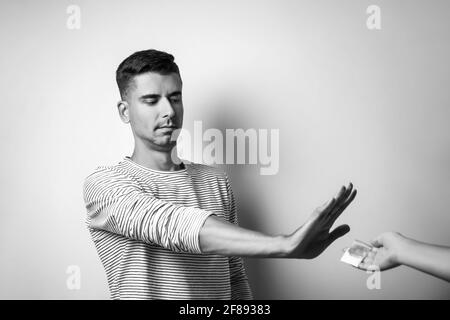 Male junkie refusing to take drugs and alcohol near light wall Stock ...