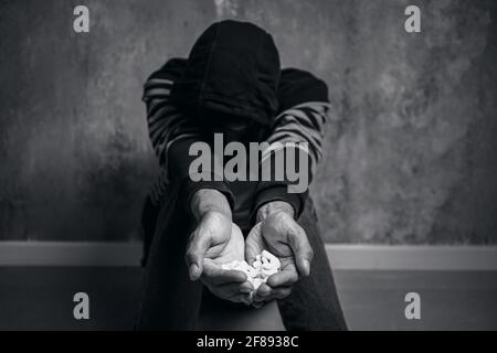 Male junkie with drugs sitting near wall outdoors Stock Photo - Alamy