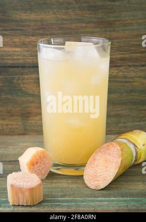 Sugarcane juice in glass with piece of sugarcane on wooden table Stock ...
