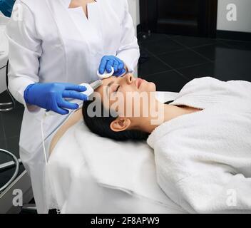 Beautiful woman while ultrasonic peel skin procedure. facial skin care ...