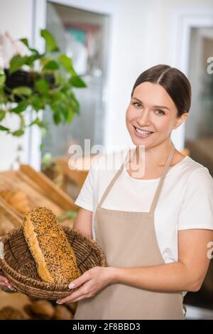 Pretty baker showing basket of bread Stock Photo - Alamy