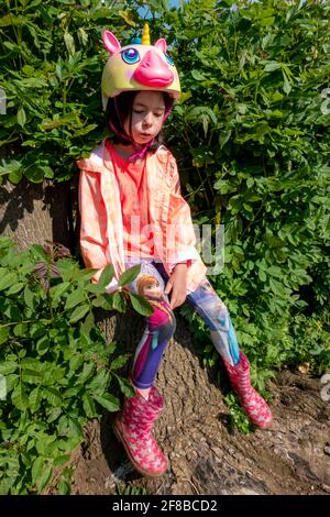Unhappy 8-year old girl waring a Raskullz unicorn cycle helmet Stock ...