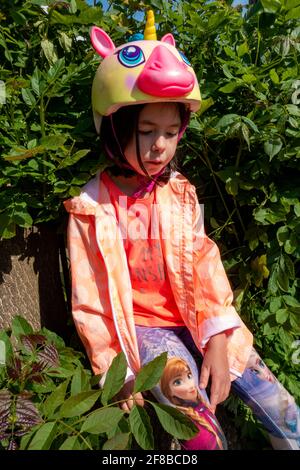 Unhappy 8-year old girl waring a Raskullz unicorn cycle helmet Stock ...