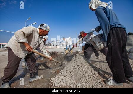 Kazakhstan, Shardara water storage dam. Group of Uzbek workers mixing ...