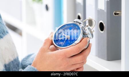 Female hands with alarm clock in bedroom, closeup. Daylight saving time ...