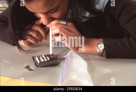 Young woman snorting cocaine lines while leaning over touchpad screen ...