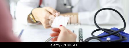 Doctor passes business card to patient at work table Stock Photo - Alamy