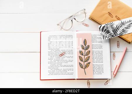 Books with bookmarks, glasses and stationery on light wooden background ...