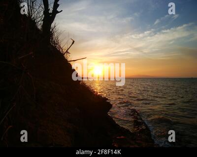 Dry hill next to the calm sea during a beautiful sunrise Stock Photo ...