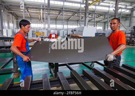 Aktau, Kazakhstan. CNC laser cutting machine and two workers with ...