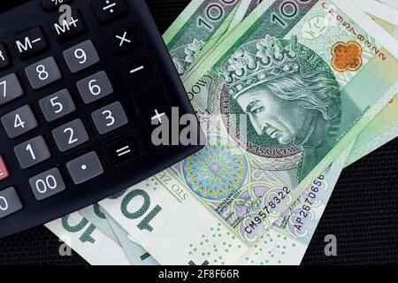 Calculator and Polish banknotes of PLN 100 and PLN 50 on a black ...