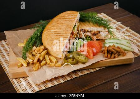 Fresh hot fragrant shawarma cut lies on a wooden board with vegetables ...