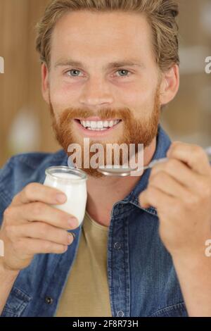 Handsome man eating delicious yogurt on violet background Stock Photo ...