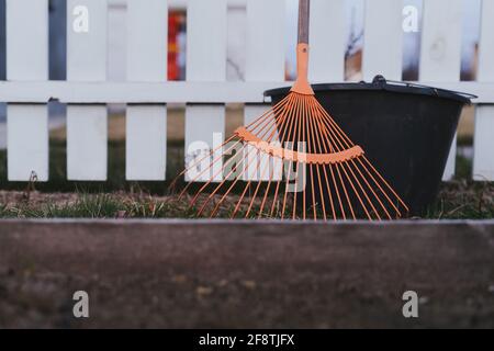 Orange bucket and black rake, gardening equipment and tool Stock Photo ...