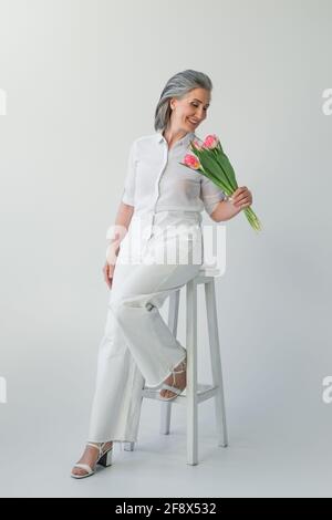 positive woman with tulips on grey background. Woman isolated face ...