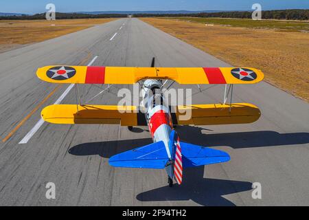A restored 1930's Boeing Stearman biplane in US Navy colours taking off ...