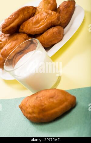 Fried three pies and glass of milk on a yellow background with copy ...