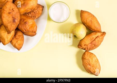 Fried three pies and glass of milk on a yellow background with copy ...