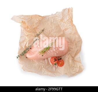 Raw chicken on parchment paper atop wooden cutting board surrounded by ...