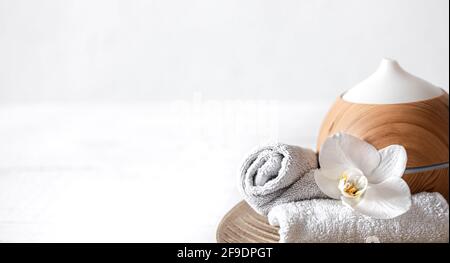 Close up of air humidifier, towel and orchid flower. Aromatherapy and ...