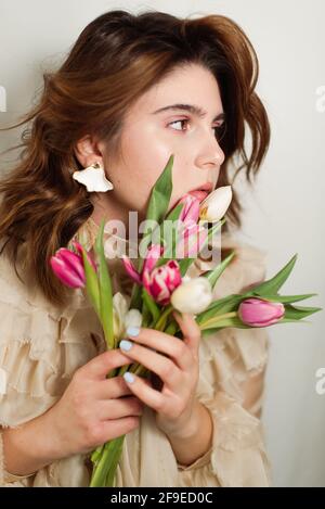 Tranquil female in hat and sweater standing with bouquet of aromatic ...