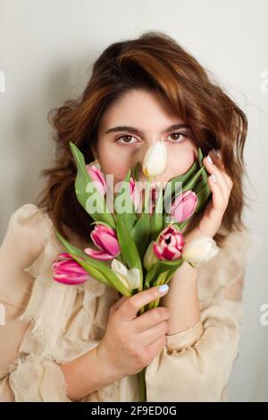 Tranquil female in hat and sweater standing with bouquet of aromatic ...
