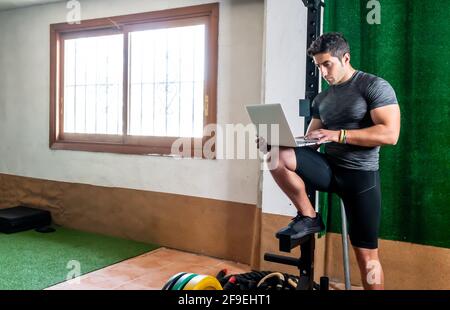 Latino coach in sportswear working out in gym with computer preparing ...