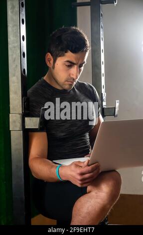 Latino coach in sportswear working out in gym with computer preparing ...