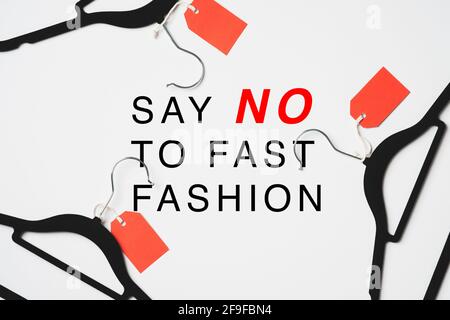 Say No To Fast Fashion sign over heap of hangers on white background ...