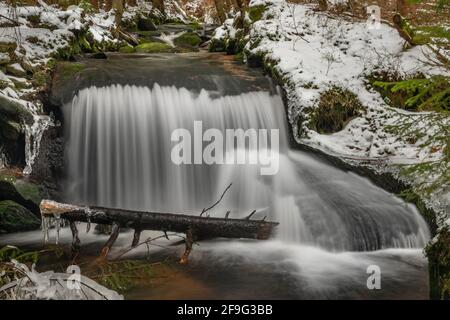 Small waterfall on color Jezerni creek in snowy spring day in national ...
