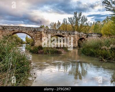 the Roman bridge Puente Canto over the river Cea along the camino of ...