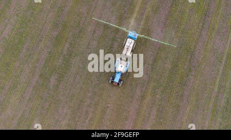 Spring field work. Early shoots. A tractor with attachments sprays ...