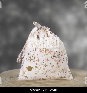 Small hygiene draw-string bag with colorful print displayed on a wooden ...