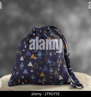 Small hygiene draw-string bag with colorful print displayed on a wooden ...