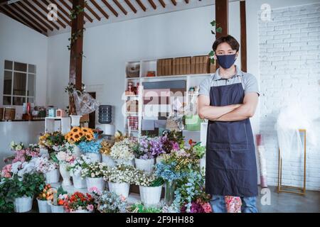 man using face mask florist standing crossed arm in front door flower ...