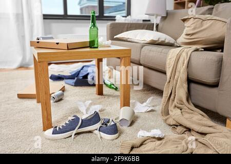 Interior of messy living room with sofa, commode and scattered clothes ...